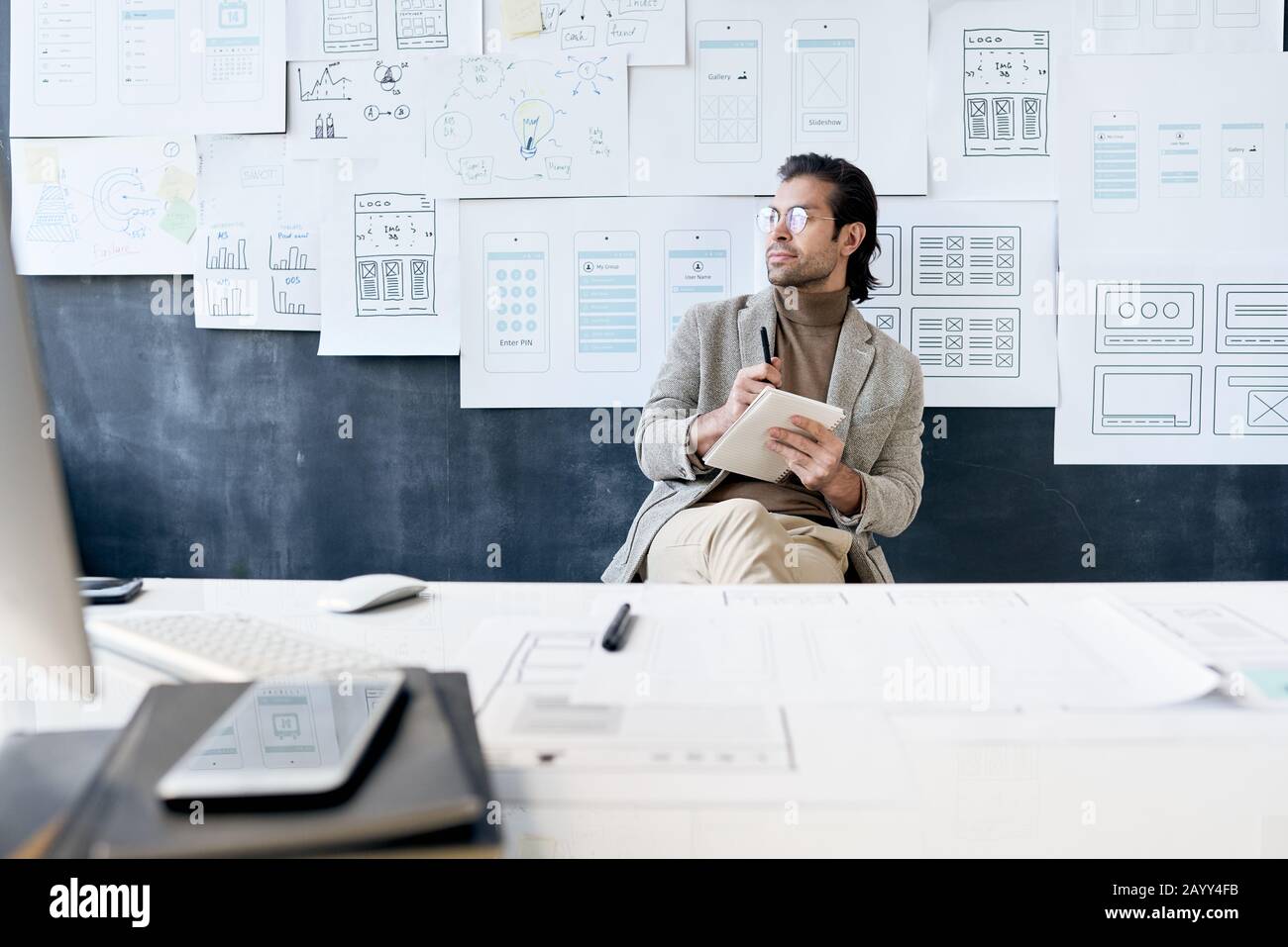 Horizontal shot of Caucasian man working on something making notes in ...