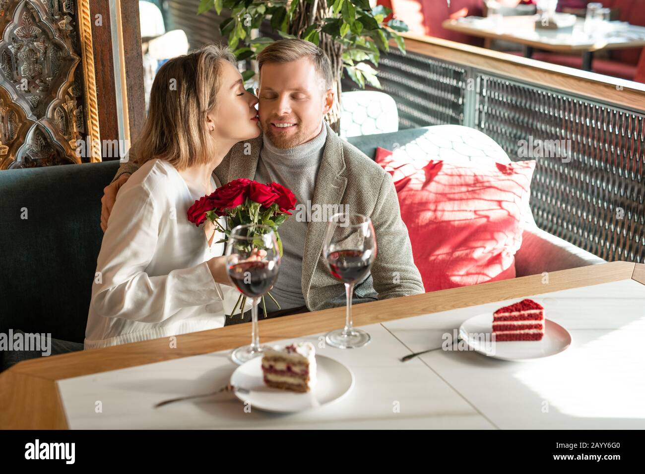 Horizontal shot of beautiful young woman holding bunch of red roses ...