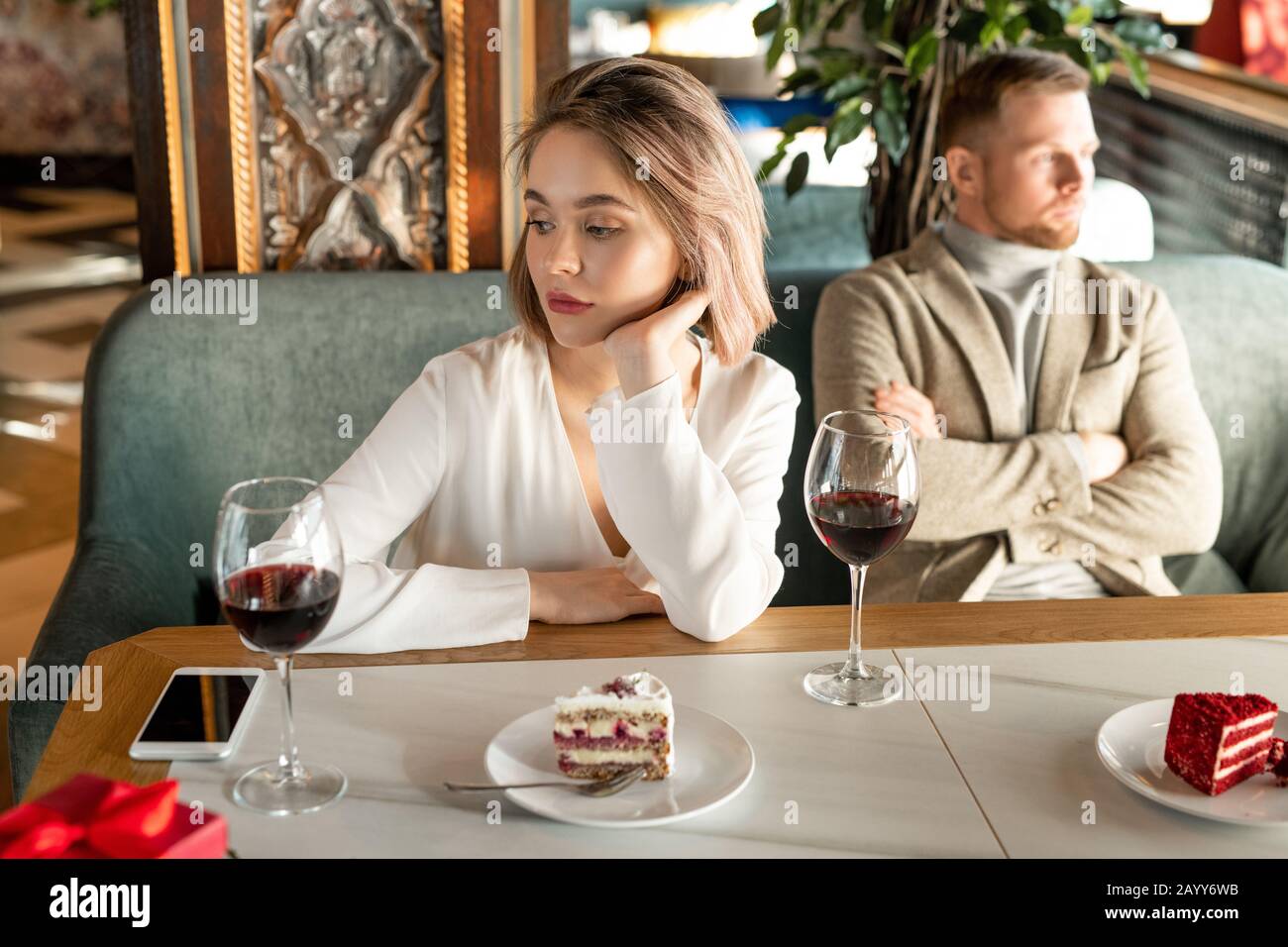 Caucasian man and woman sitting together in restaurant with resentful ...