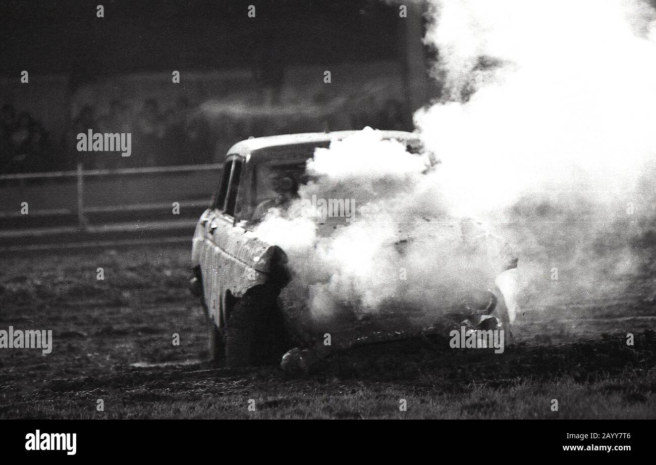 1970s, historical, a banger racing car with smoke pouring out from a ...