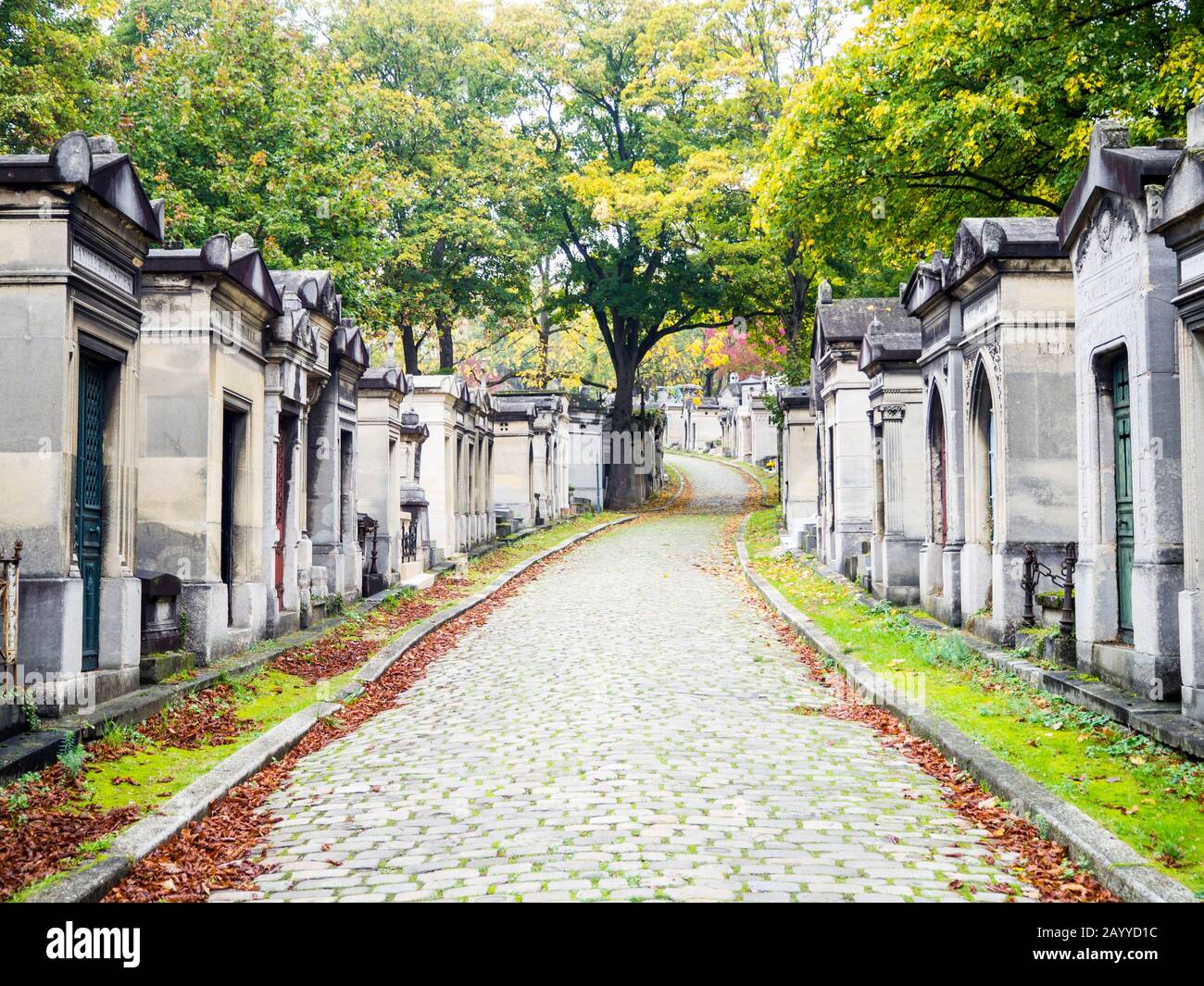 Cobblestone pathway in a monumental cemetery with funeral grey chapels ...