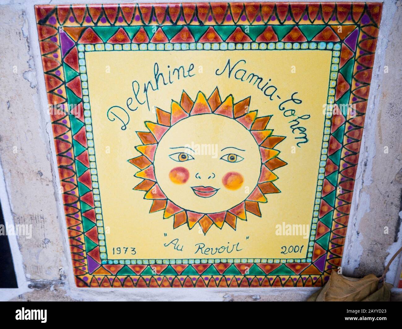Colorful tombstone of a lady with a picture of a sun and two sets of ...