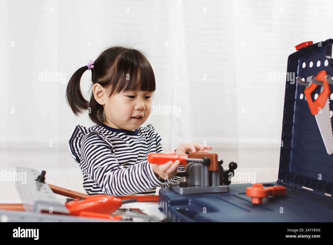 toddler girl pretend using DIY tool at home against white backgrround ...
