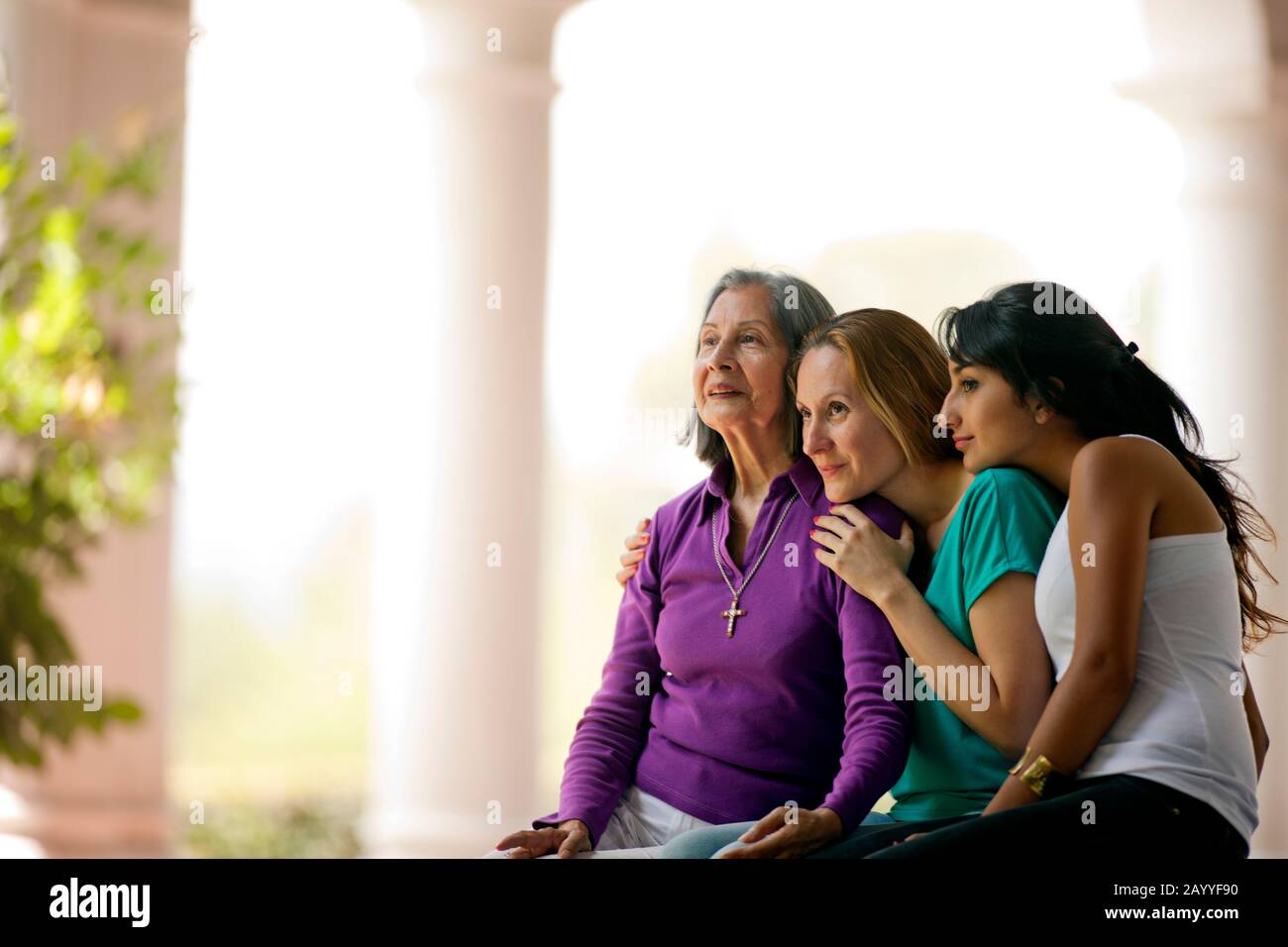 Three women leaning in to each other while sitting side by side on a ...
