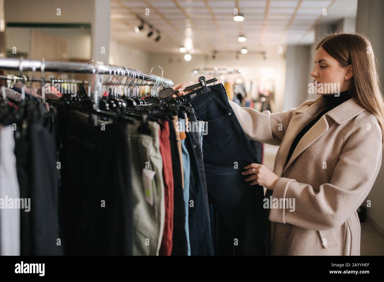 Young beautiful woman looking for new jeans in clothing store Stock ...