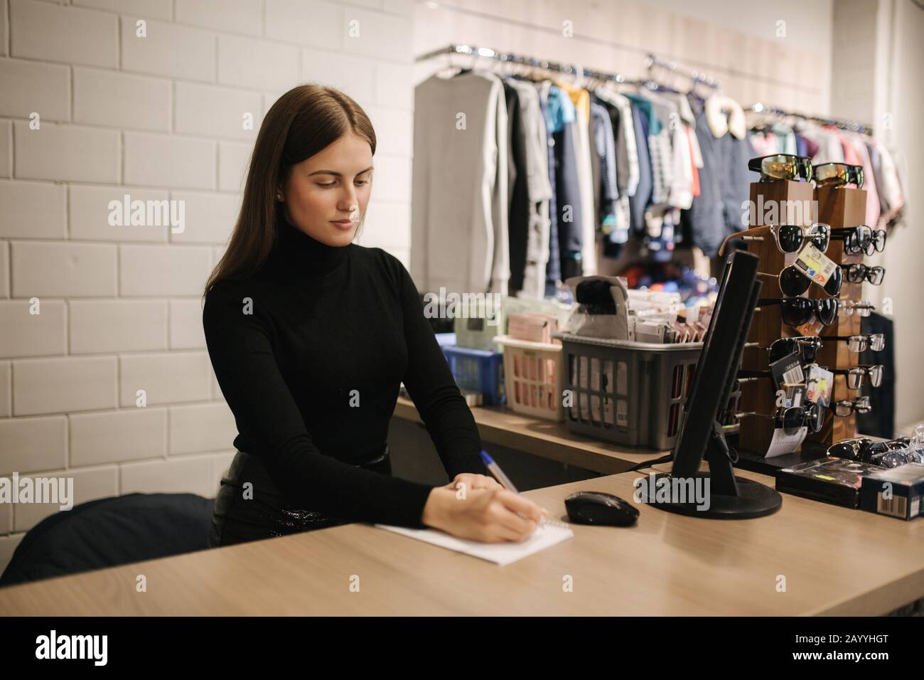 Young shop assistant in clothes store working by comtuper. Beautiful ...