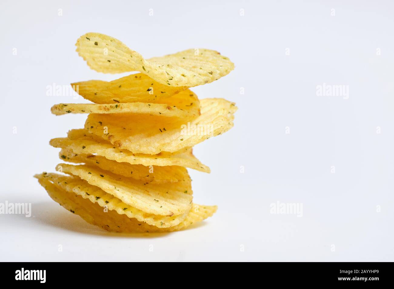 A vertical stack of potato chips with spices on a white background ...