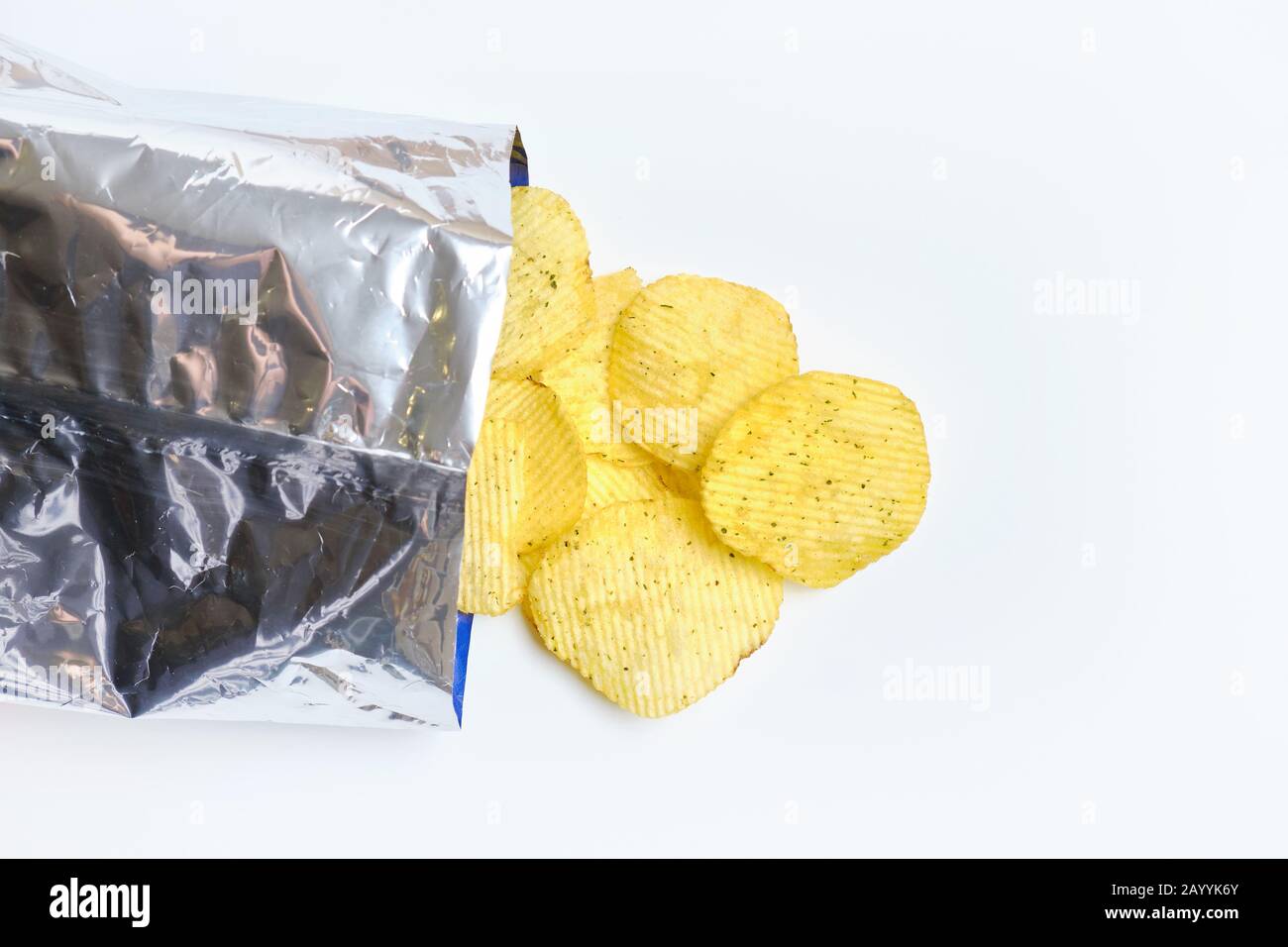Chips are falling out of foil packaging on a white background. Close up ...