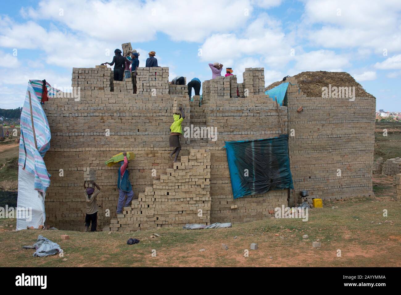 Bricks made out of clay are being stacked to be burned near ...