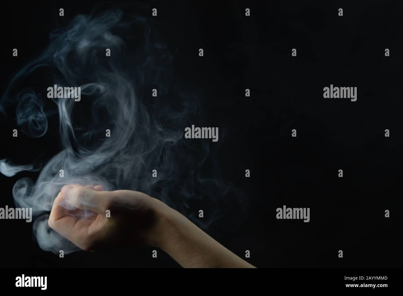 Smoke in hand. abstract fog in the dark. hand creates a magic spell ...