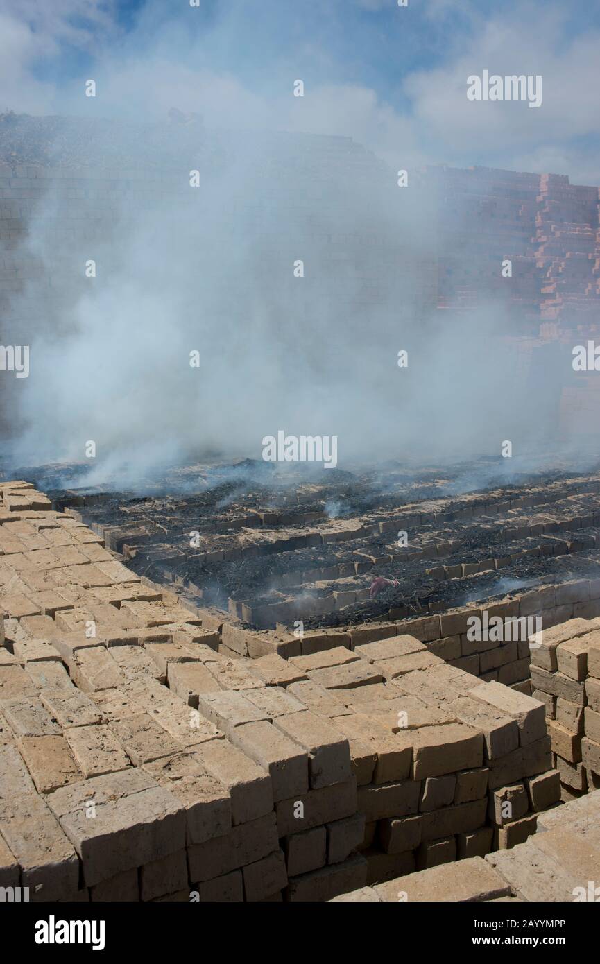 Bricks made out of clay are being burned using charcoal in kiln near ...
