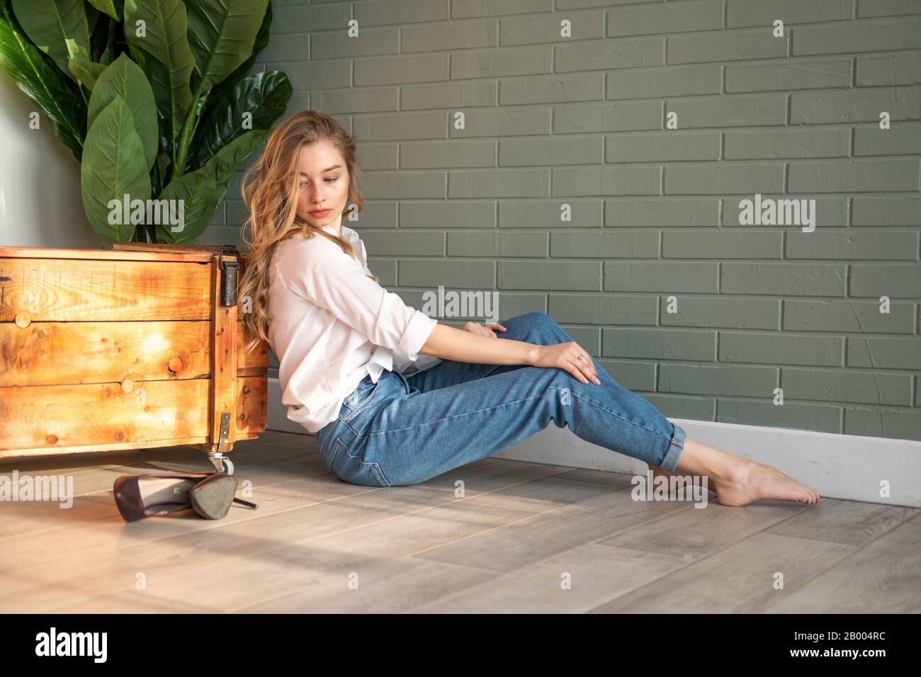 Young beautiful woman sitting on the floor with bare feet next to ...