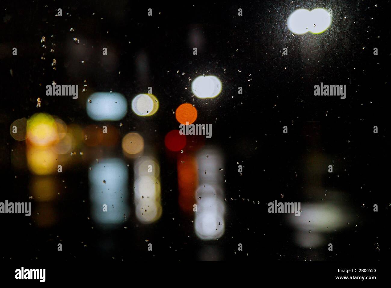 Rain drops on car window with road light bokeh in night in rainy season ...