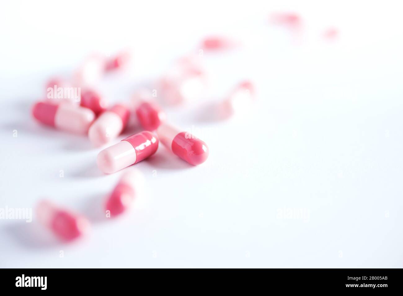 Pink capsules, pills, vitamins on white background. Copy space. Bunch ...