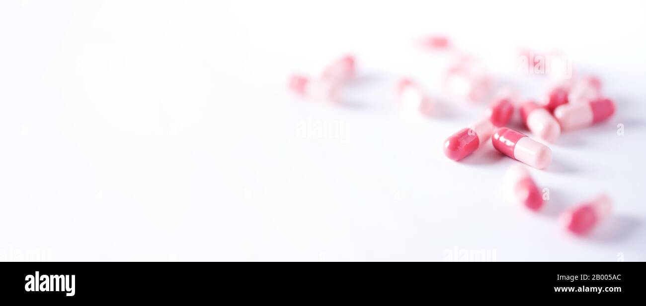 Pink capsules, pills, vitamins on white background. Copy space. Bunch ...