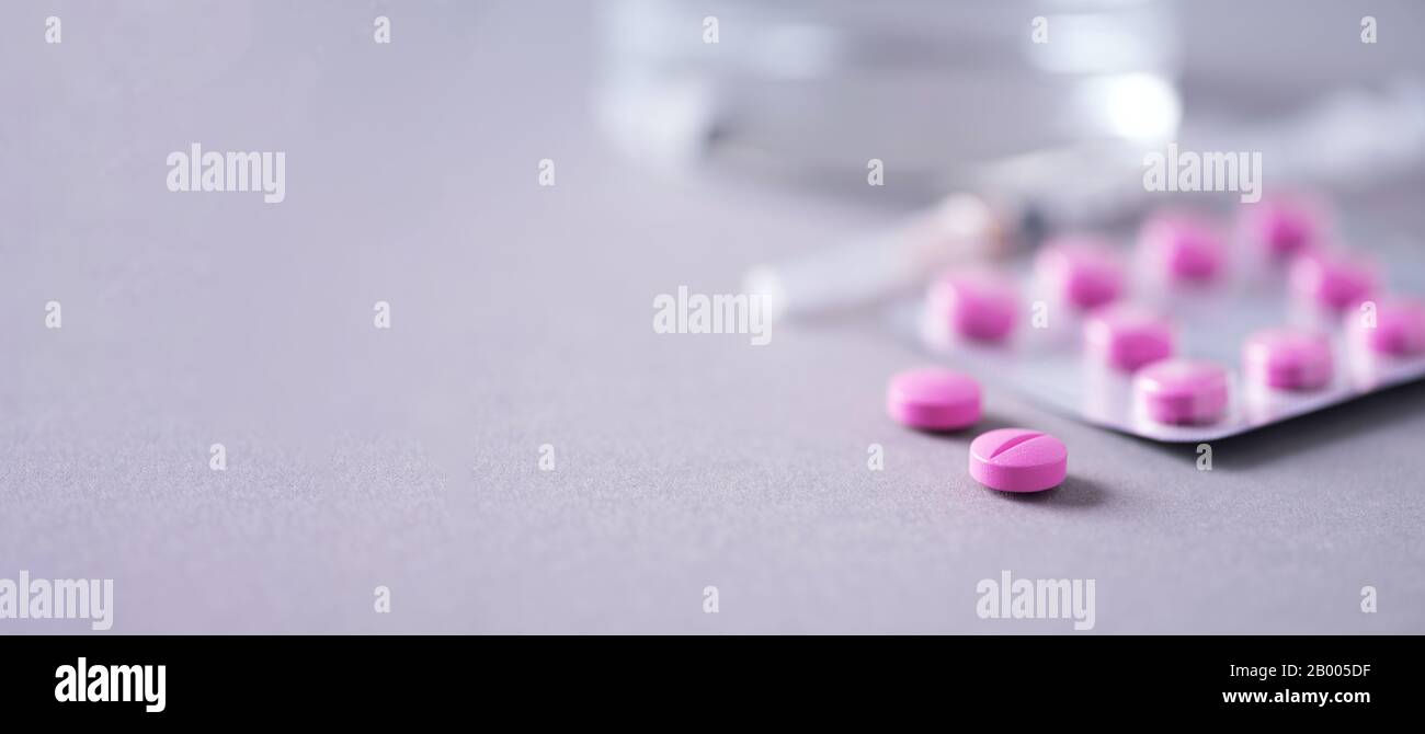 Pink capsule, pills, vitamins on grey background. Copy space. Bunch of ...