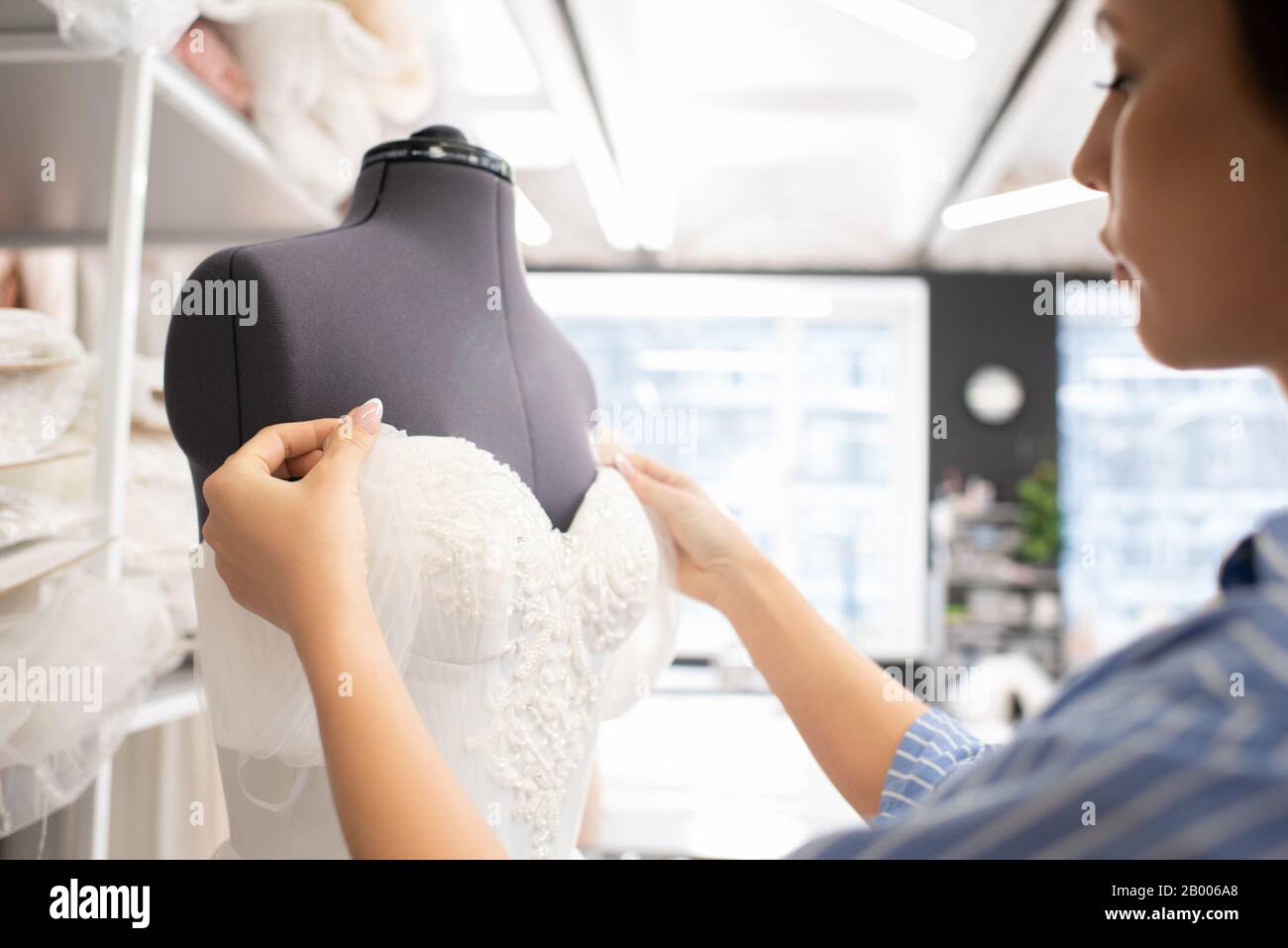 Professional seamstress working on wedding dress corset in bridal ...