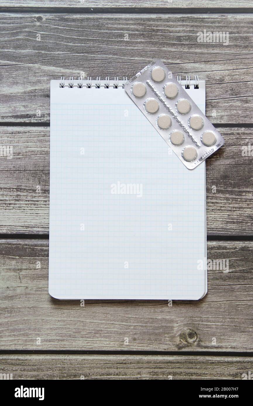 Notepad with a blank white sheet in a checker paper with pills in a ...