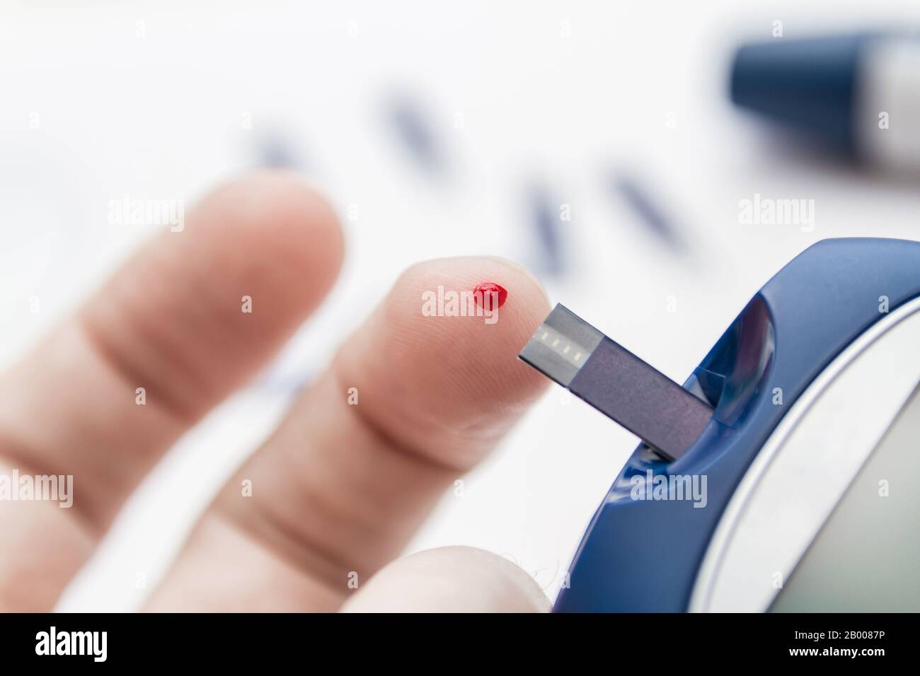 Man brings your finger to the test strip of the blood glucose meter ...