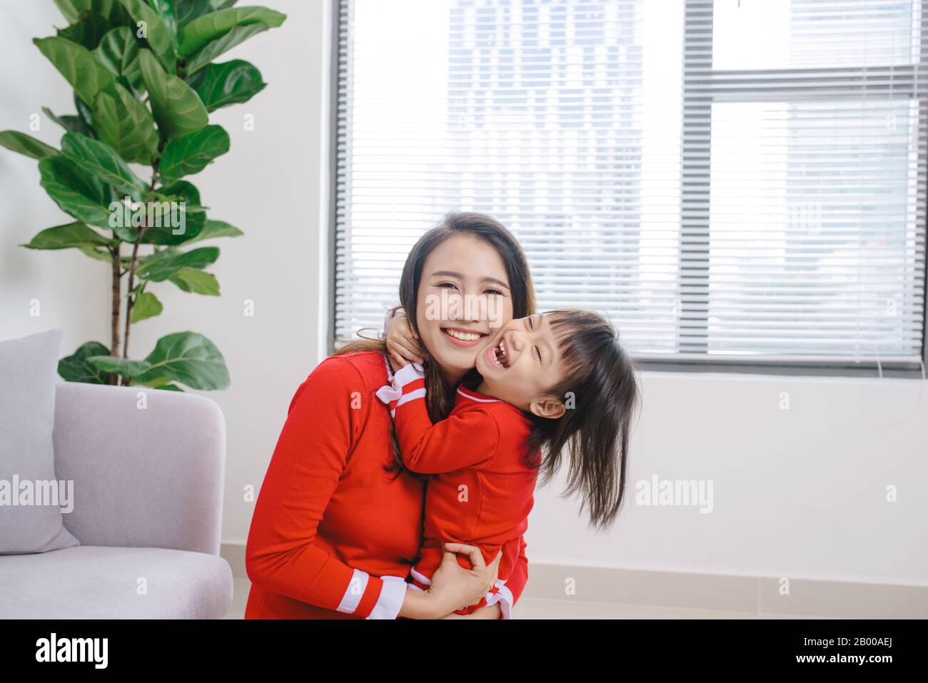 Attractive young mother hugging her little daughter at home Stock Photo - Alamy