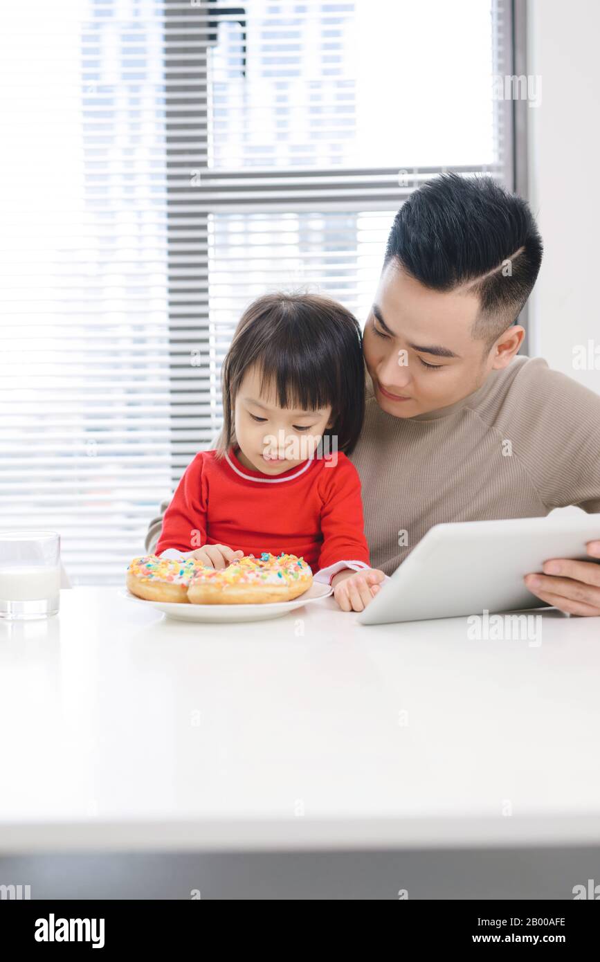 Young dad and his daughter eating pizza and using ipad Stock Photo - Alamy