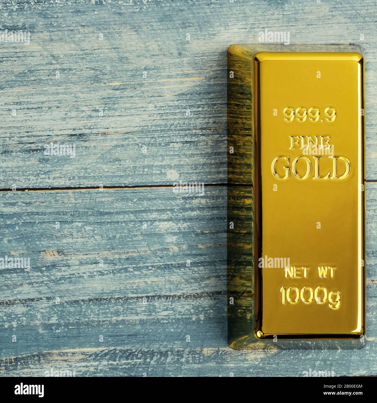 Ingot of pure gold metal bullion on a background of blue wooden boards ...