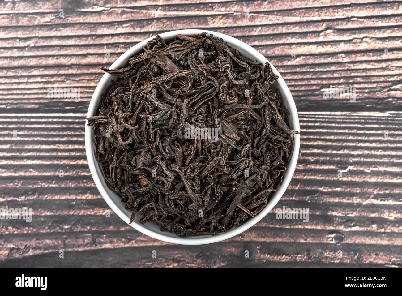Dried tea is poured into a ceramic cup on a wooden plank table. View ...