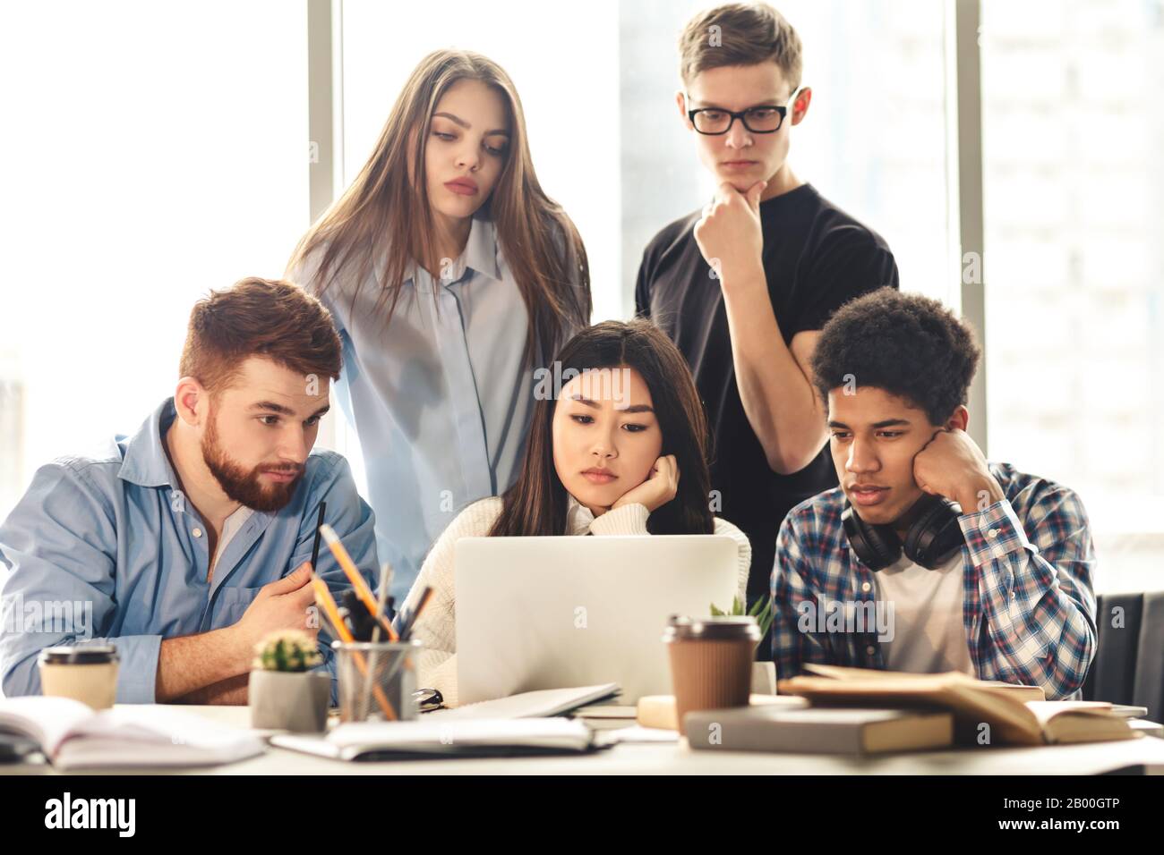 Serious groupmates searching information for their project Stock Photo ...