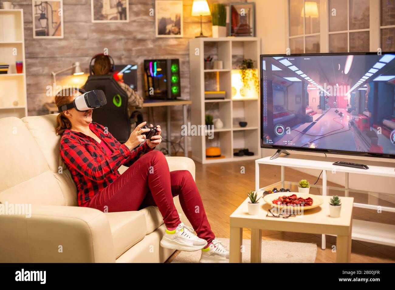 Woman gamer playing video games using a VR headset late at night in the ...