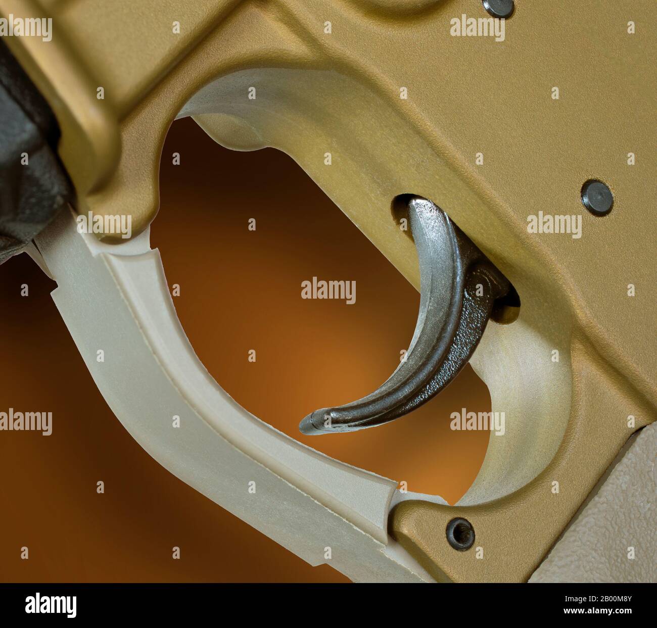 Brass looking AR-15 with black trigger and shadow on brown background ...