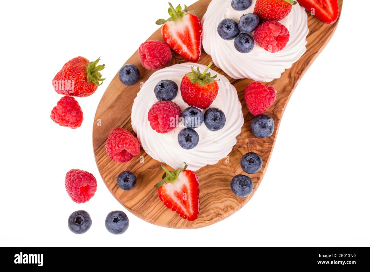 Summer fruit pavlova displayed on olive wood board, over white ...