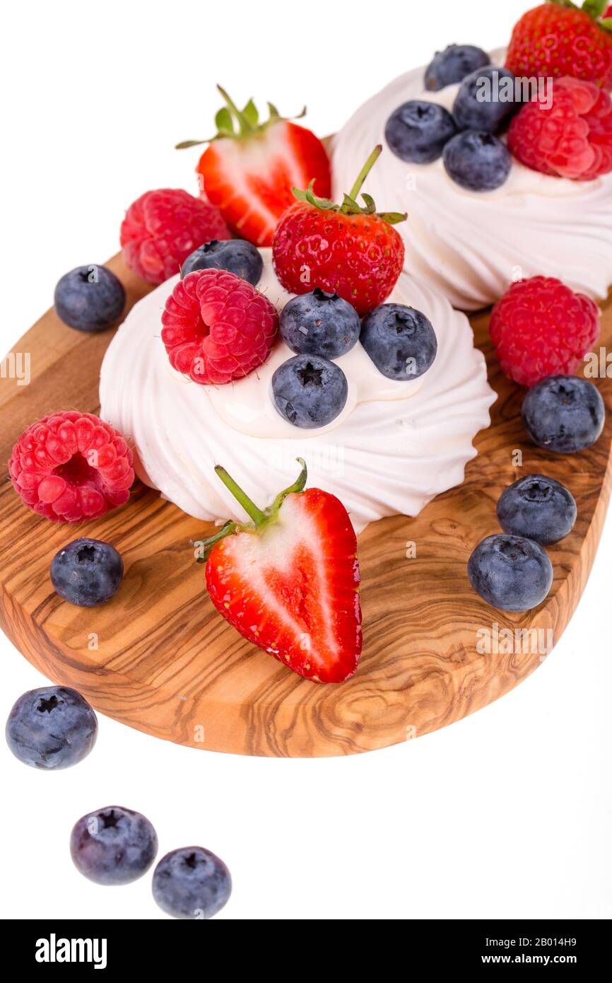 Summer fruit pavlova displayed on olive wood board, over white ...
