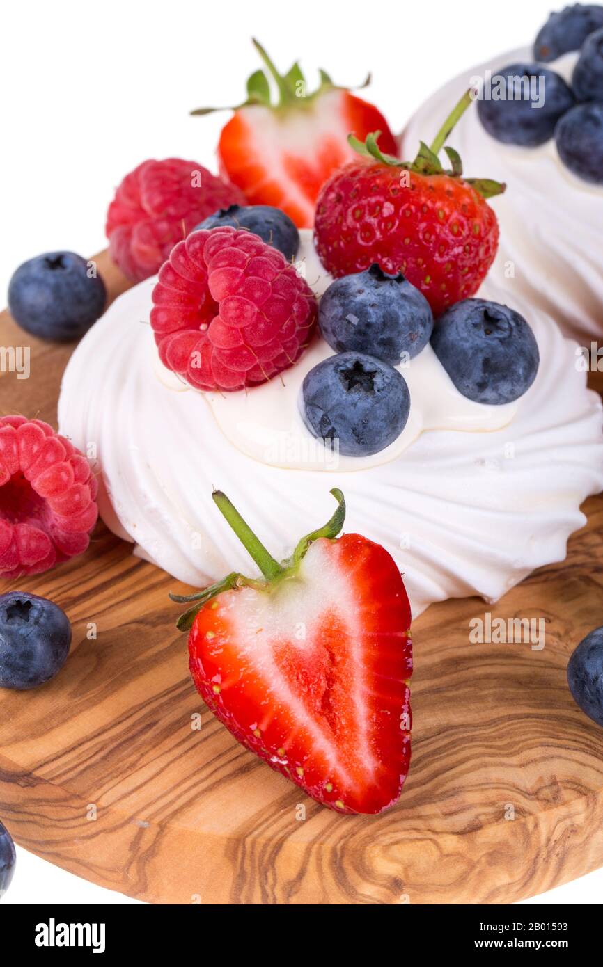 Summer fruit pavlova displayed on olive wood board, over white ...
