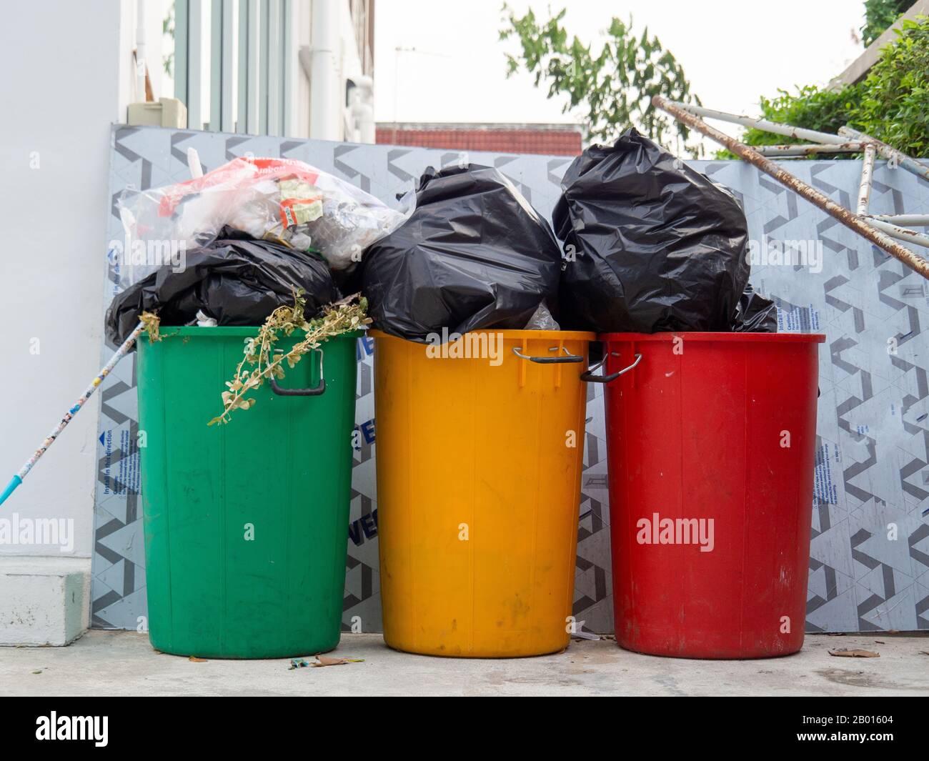 Green, yellow, and red bins that are full of trash Stock Photo - Alamy