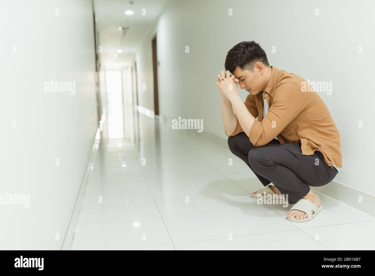 depressed man who lost faith sitting alone in a corridor Stock Photo ...