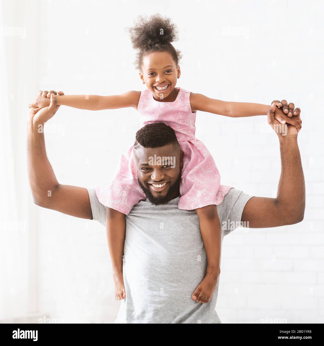 Black young dad carrying his little princess daughter on shoulders Stock Photo - Alamy