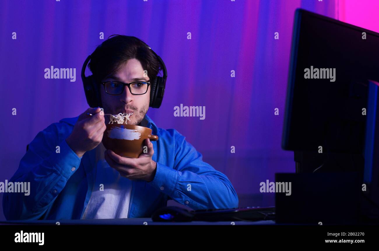 Gamer Eating Noodles At Computer Playing Games Online At Home Stock ...