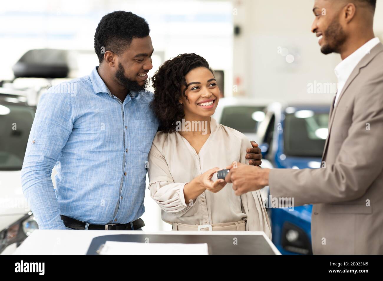 Dealer Giving New Car Key To Buyers Standing In Store Stock Photo - Alamy