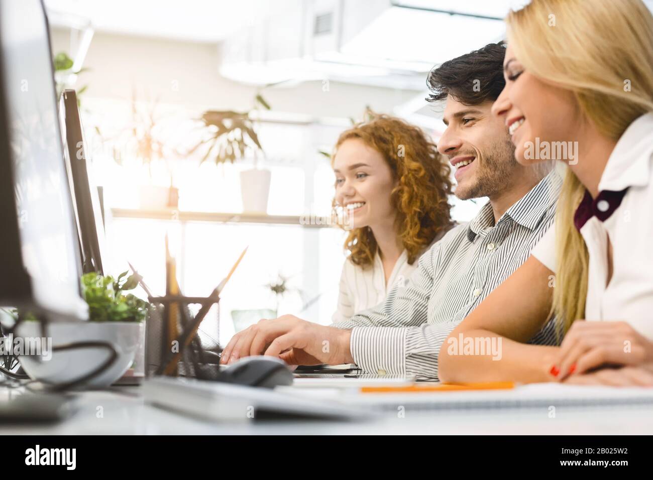 Professional business team working together, looking at desktop screens ...