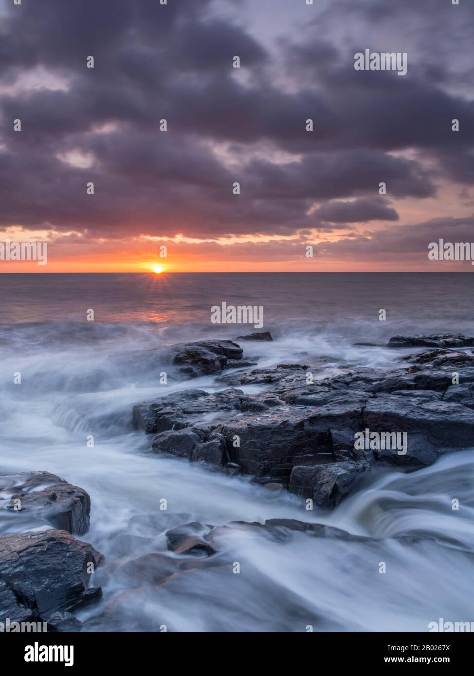 Sunrise over the volcanic dolerite rocks of Craster, Northumberland ...