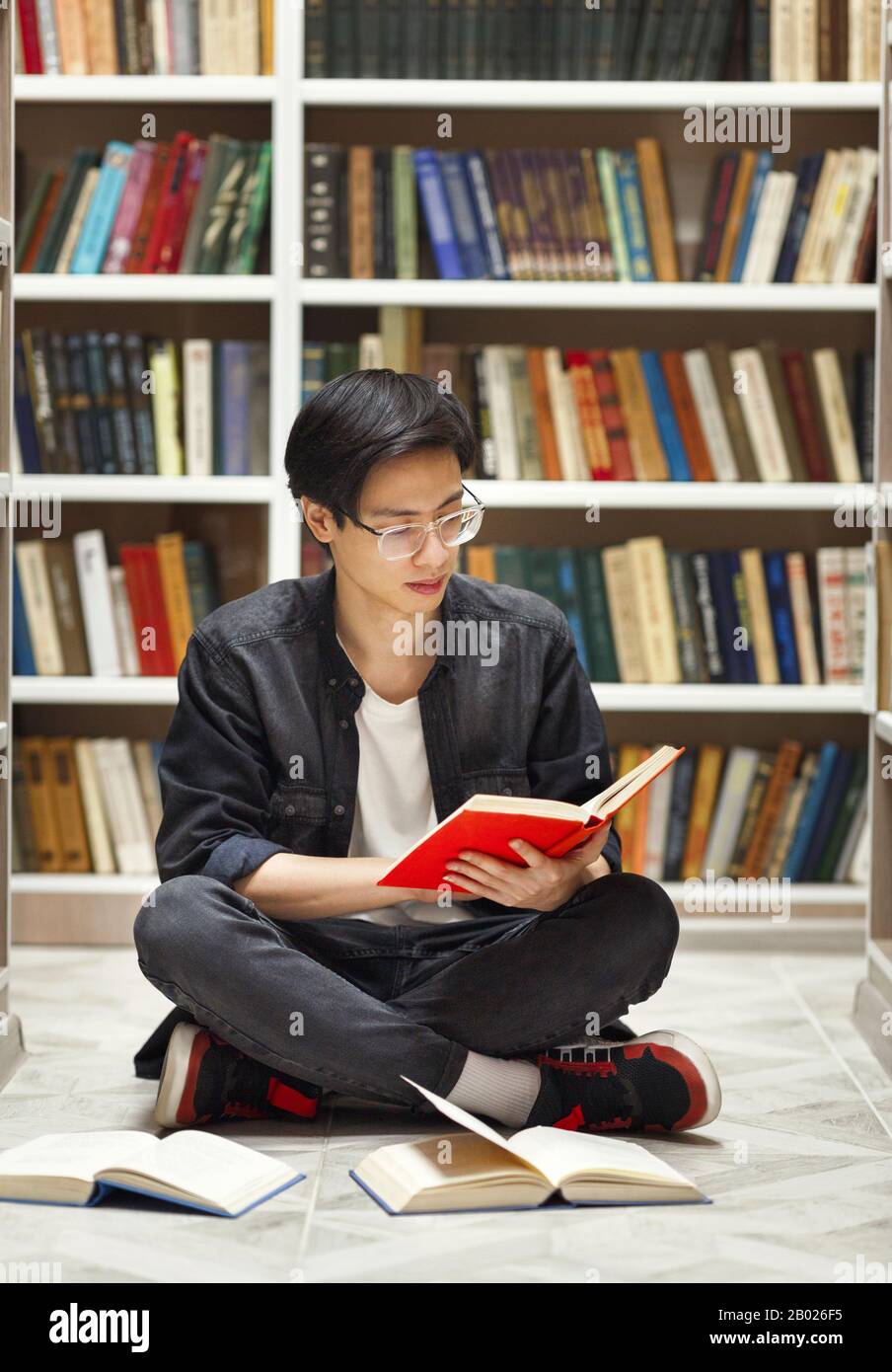 Smiling korean guy reading books at library Stock Photo - Alamy