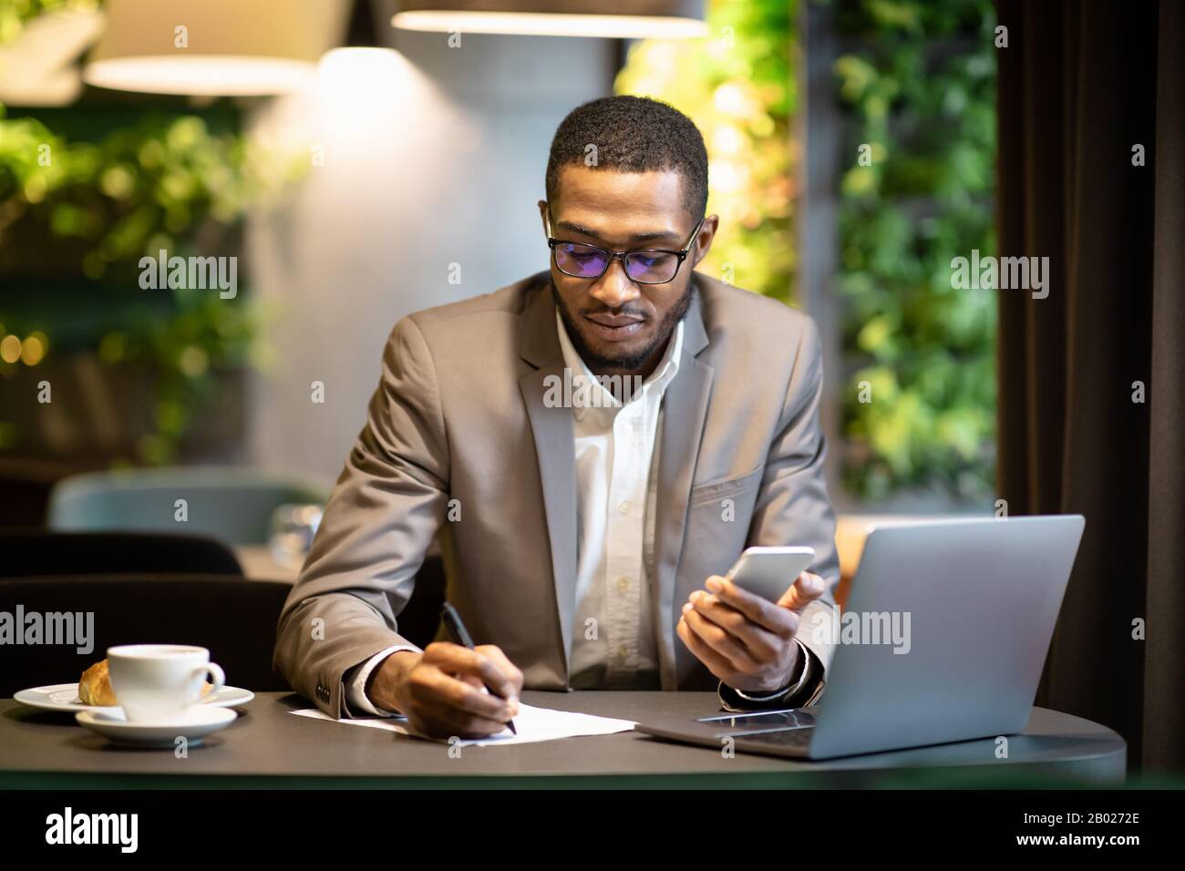 Black business man taking notes holding phone Stock Photo - Alamy
