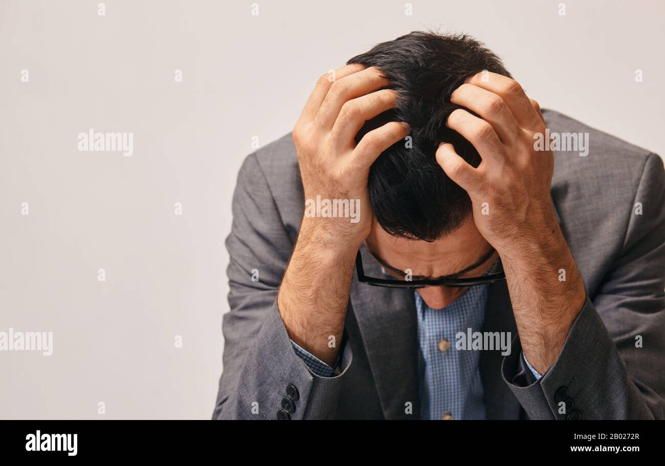 a young man holding his head. he is very concerned Stock Photo - Alamy