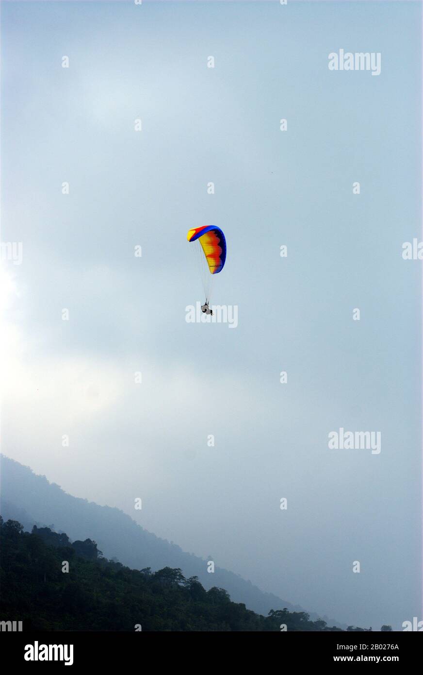 A paragliding athlete are flying in misty air with his parachute above ...