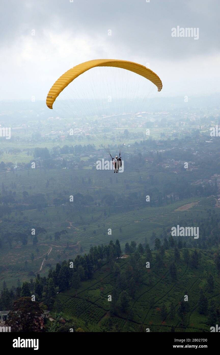 A paragliding athlete are flying in misty air with his parachute above ...