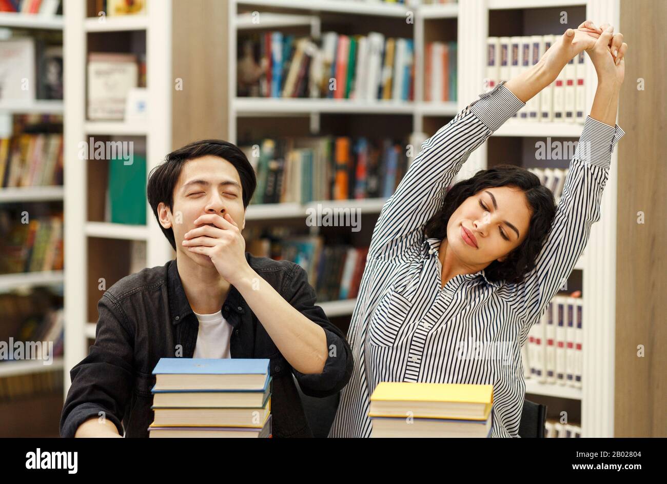 Tired students yawning and stretching in the campus library Stock Photo ...
