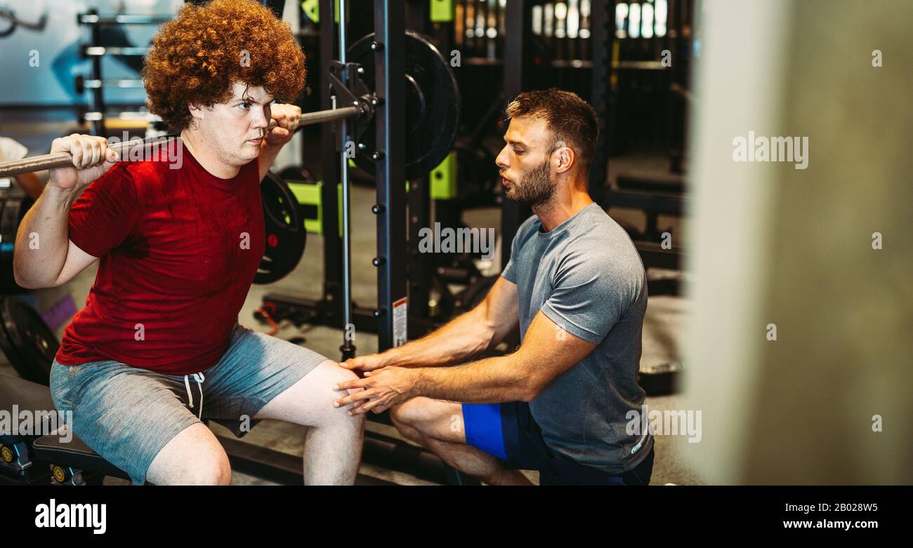 Overweight young man exercising gym with personal trainer Stock Photo ...