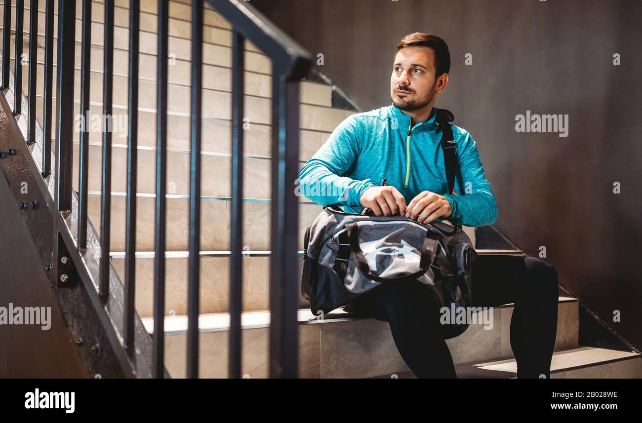 Happy fit man relaxing in the gym after strength exercises for ...