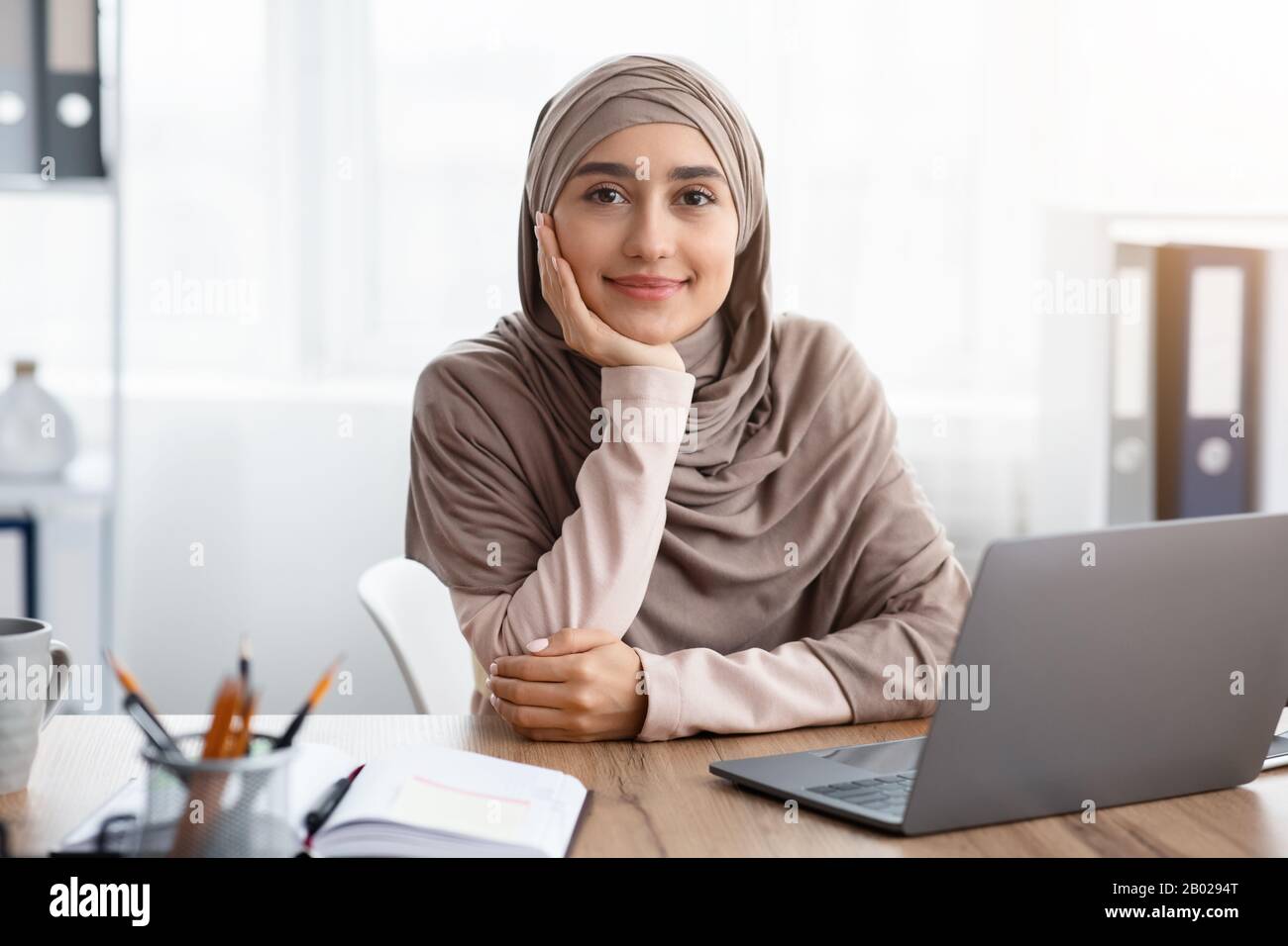 Portrait of muslim female entrepreneur sitting at workplace in modern ...
