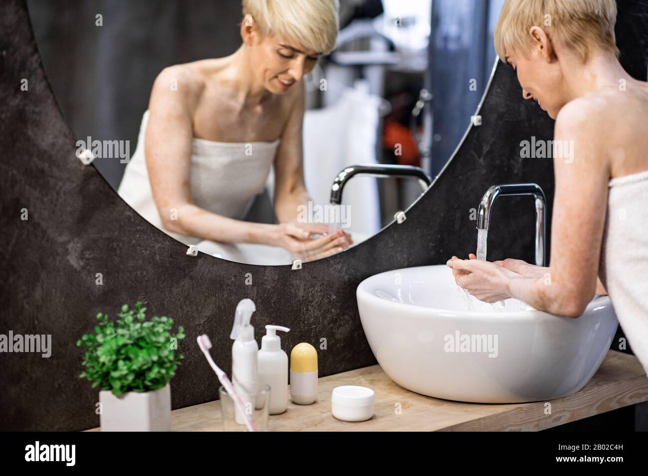 Lady Washing Face Standing Wrapped In Towel In Bathroom Stock Photo - Alamy
